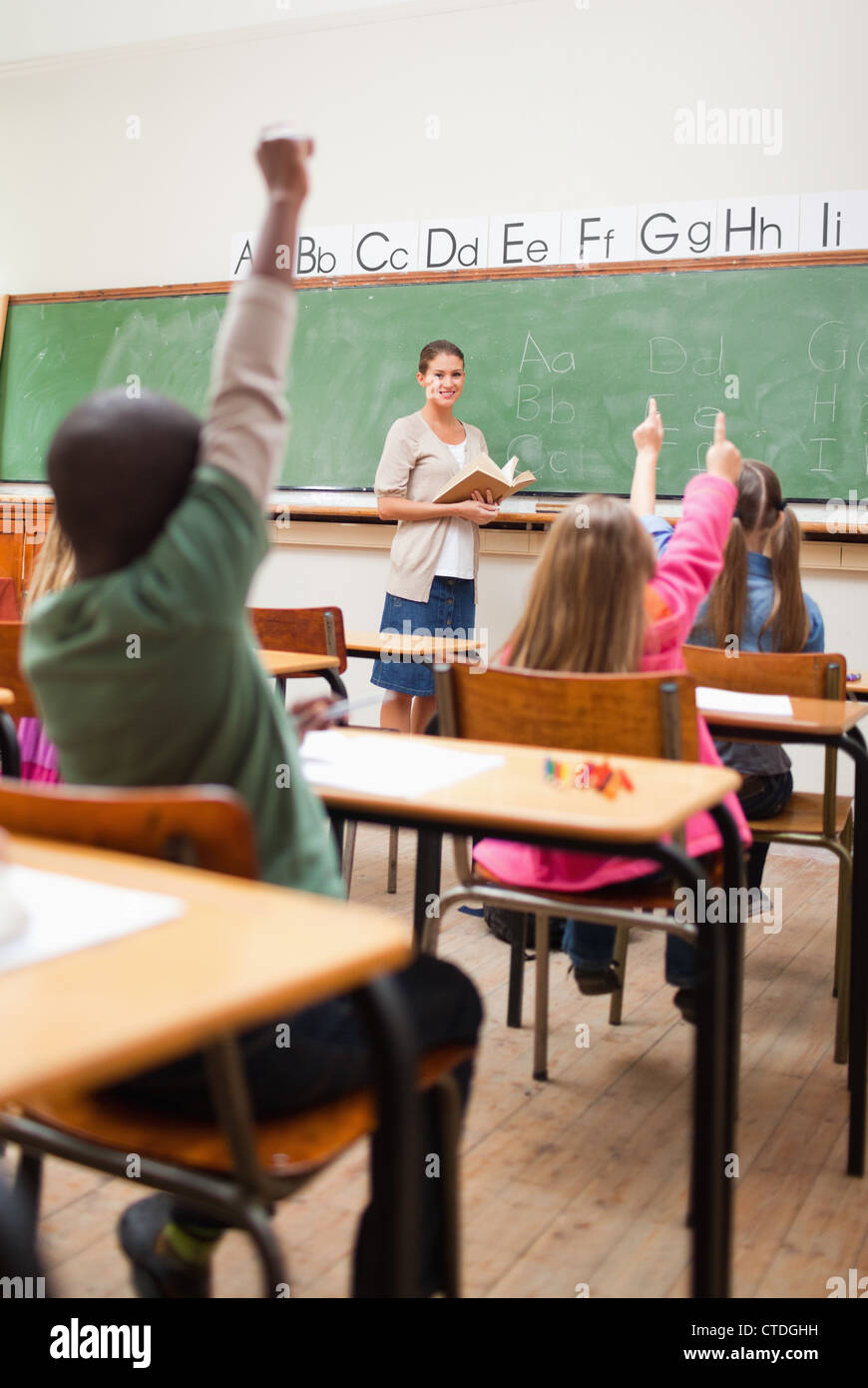 Back view of elementary school students rising hands Stock Photo - Alamy