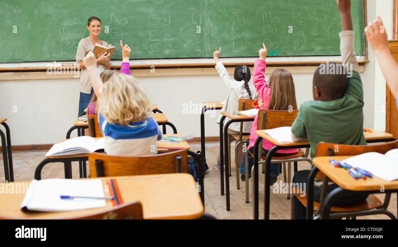 Back view of elementary students raising hands Stock Photo - Alamy