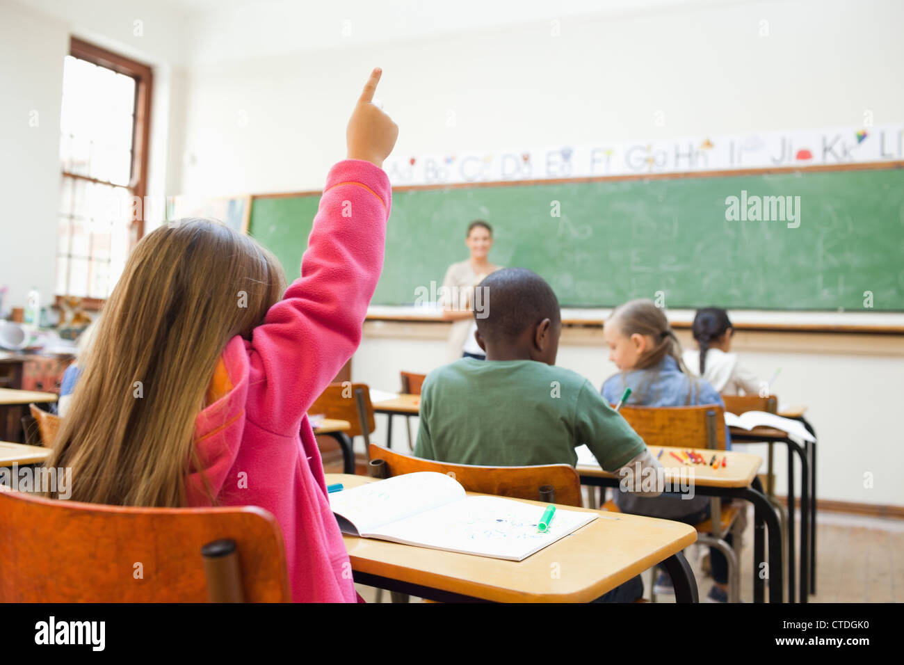 Girl raising hand during lesson Stock Photo - Alamy