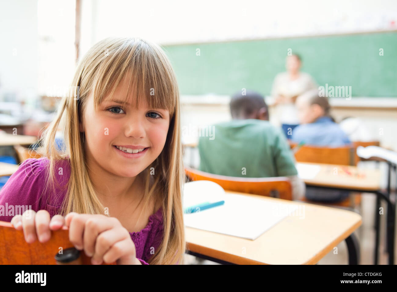 Smiling girl turning around during lesson Stock Photo - Alamy