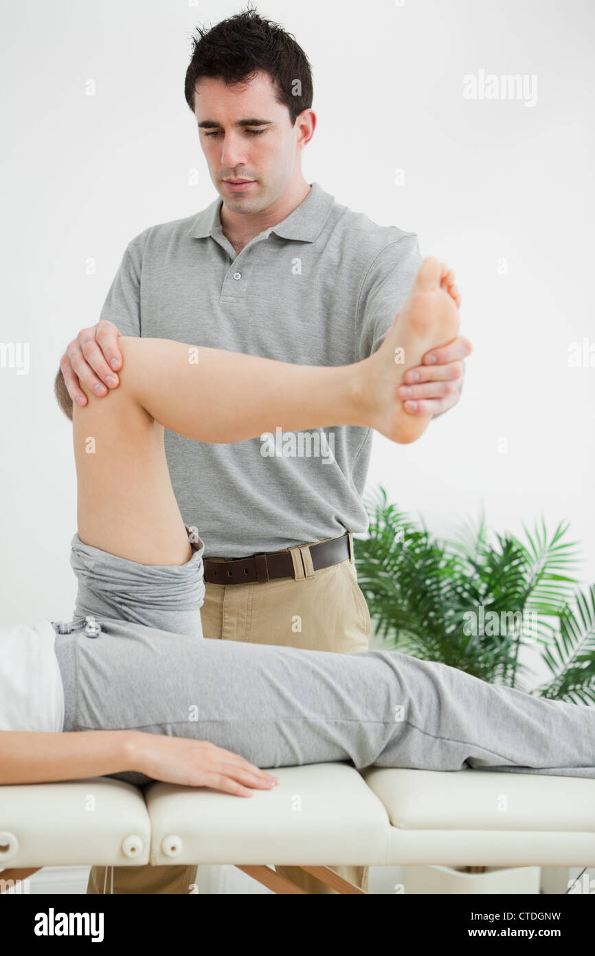 Brunette physiotherapist manipulating a leg Stock Photo - Alamy