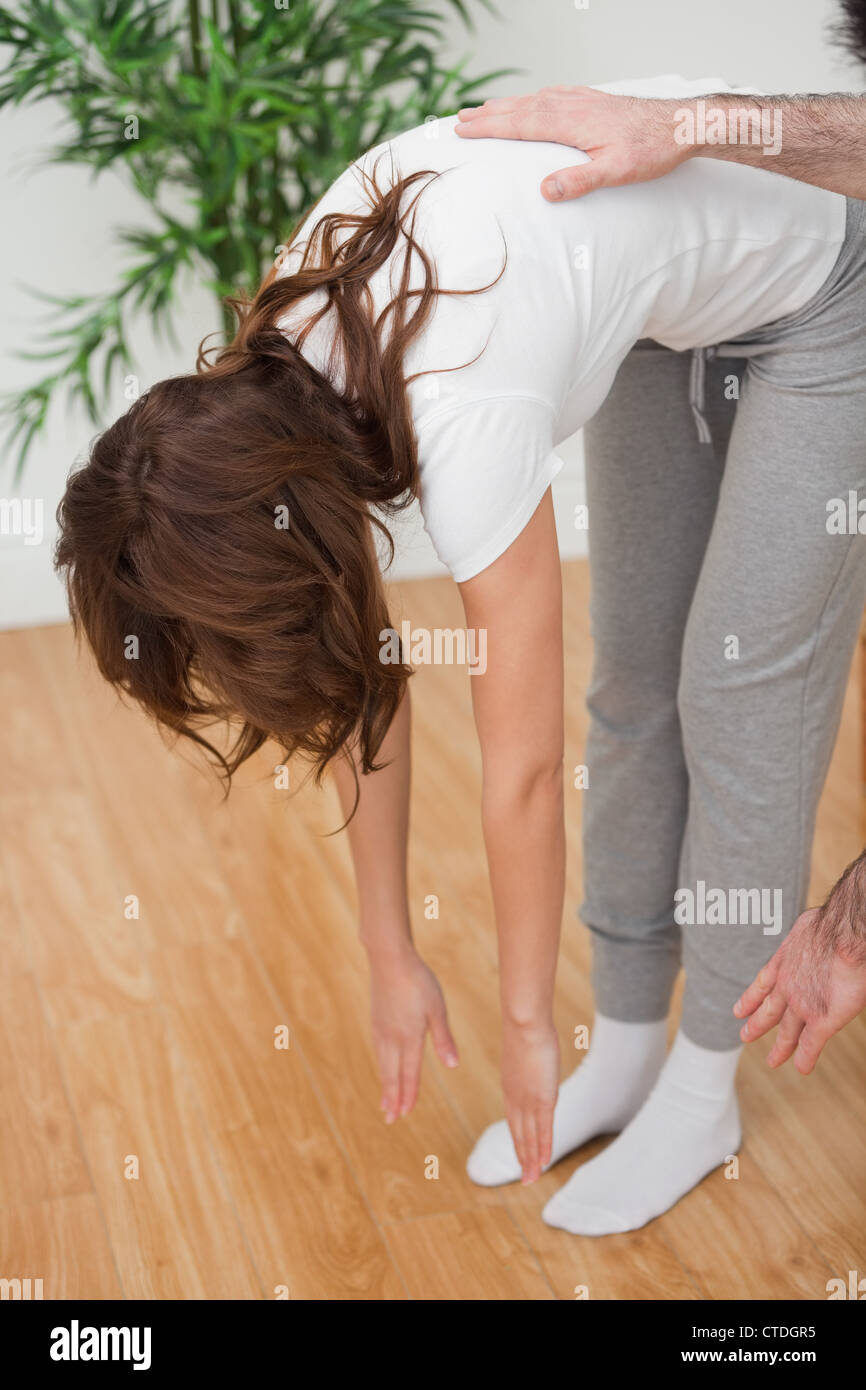 Woman standing while touching her feet with her hands Stock Photo - Alamy