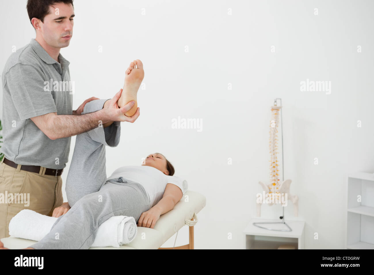 Brunette physiotherapist manipulating the leg of a woman Stock Photo ...