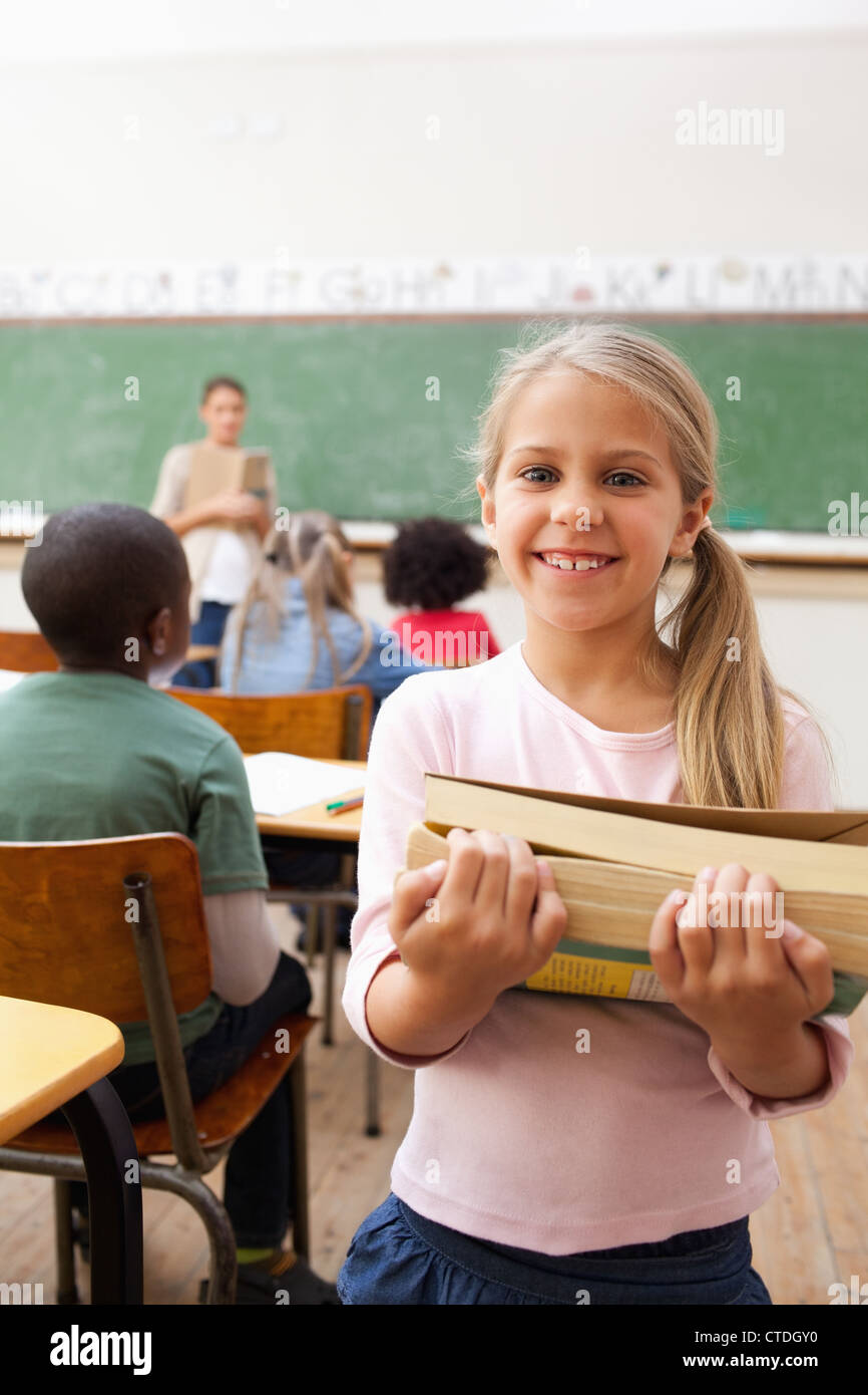 Smiling student with stack of books in classroom Stock Photo - Alamy