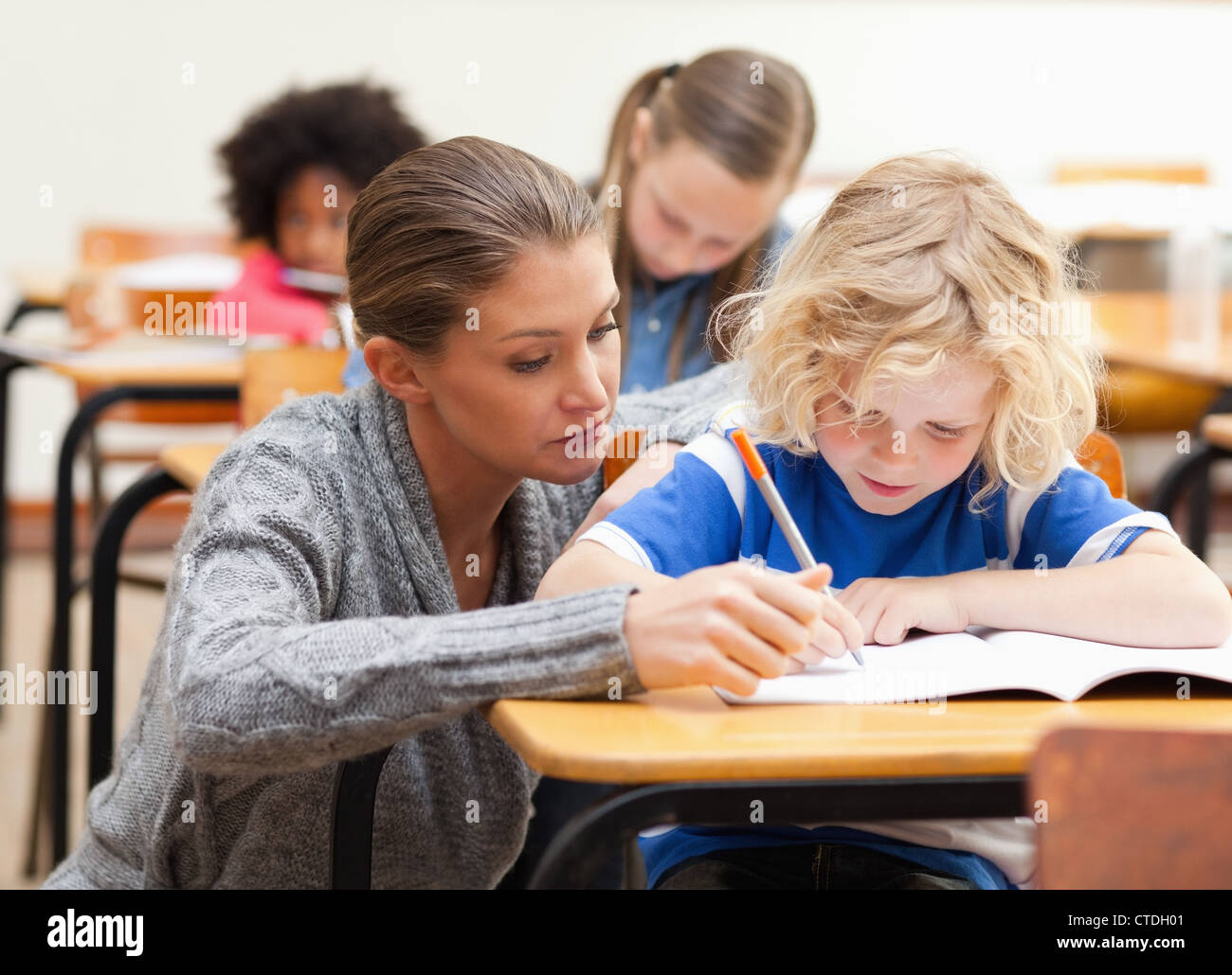 Helpful teacher next to a student Stock Photo - Alamy