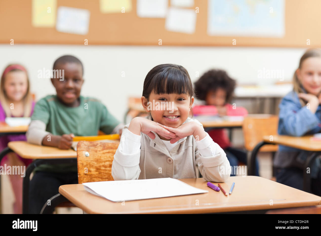 Smiling pupil sitting at her desk Stock Photo - Alamy