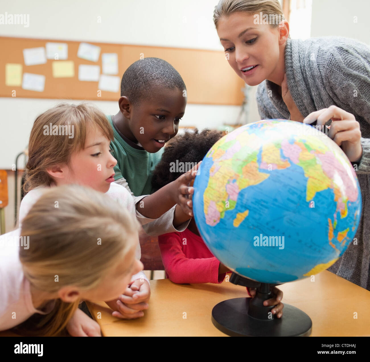 Teacher pointing globe in classroom hi-res stock photography and images ...