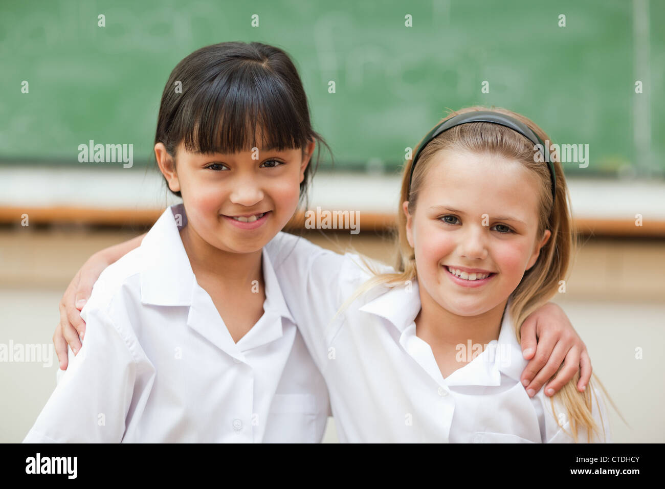 Happy girls in school uniform in front of blackboard Stock Photo - Alamy