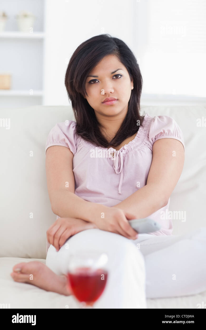 Woman sitting on a couch while crossing her arms and holding a ...