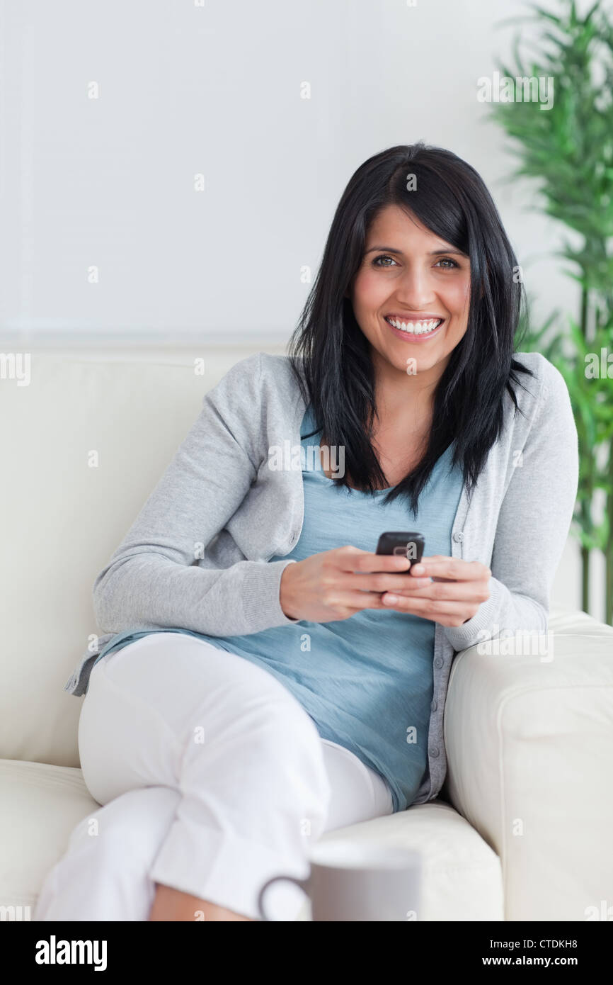Woman holding a telephone while relaxing on a sofa Stock Photo - Alamy
