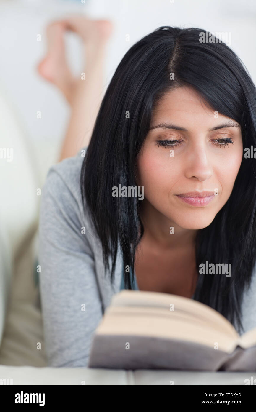 Woman reading a book while laying on a couch Stock Photo - Alamy