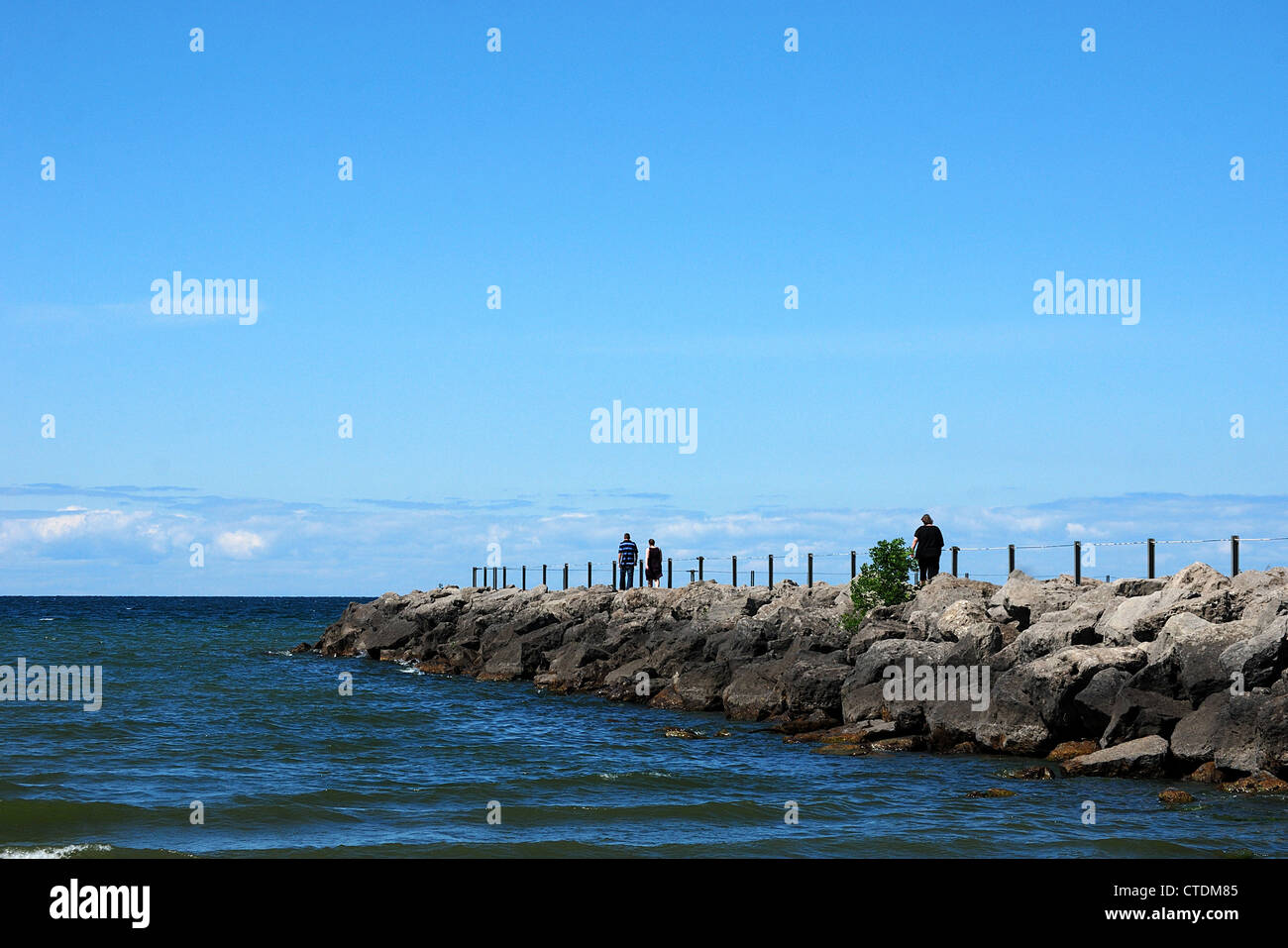 Three people walk to end of pier Stock Photo - Alamy