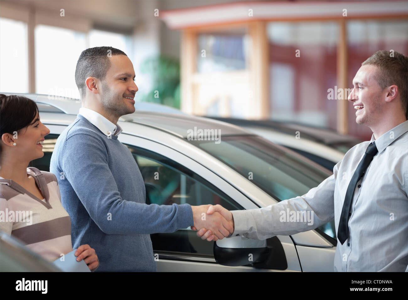 Smiling salesman shaking a customer hand Stock Photo - Alamy