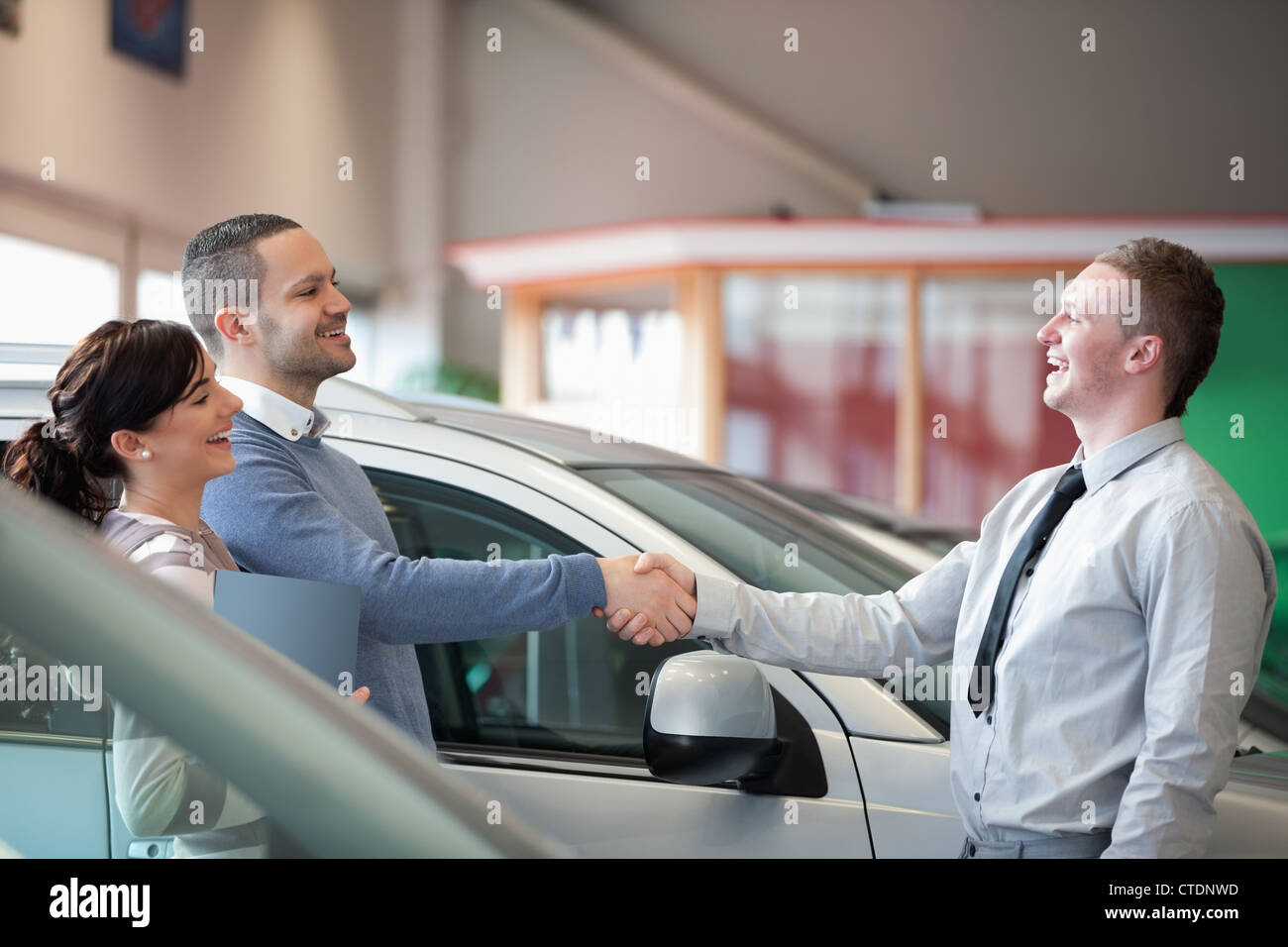 Salesman smiling while shaking the hand of a customer Stock Photo - Alamy