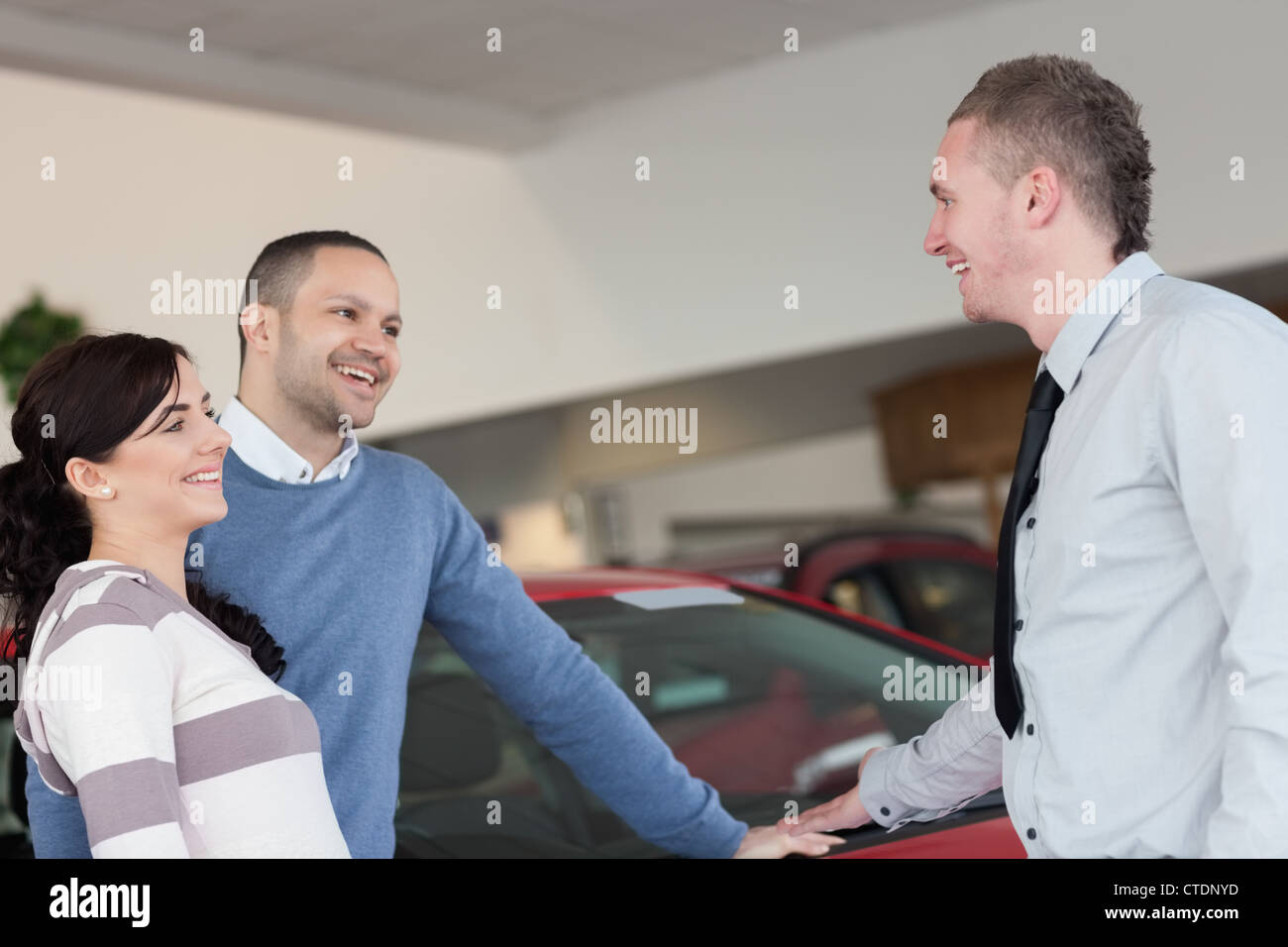 Laughing couple talking with a salesman Stock Photo - Alamy