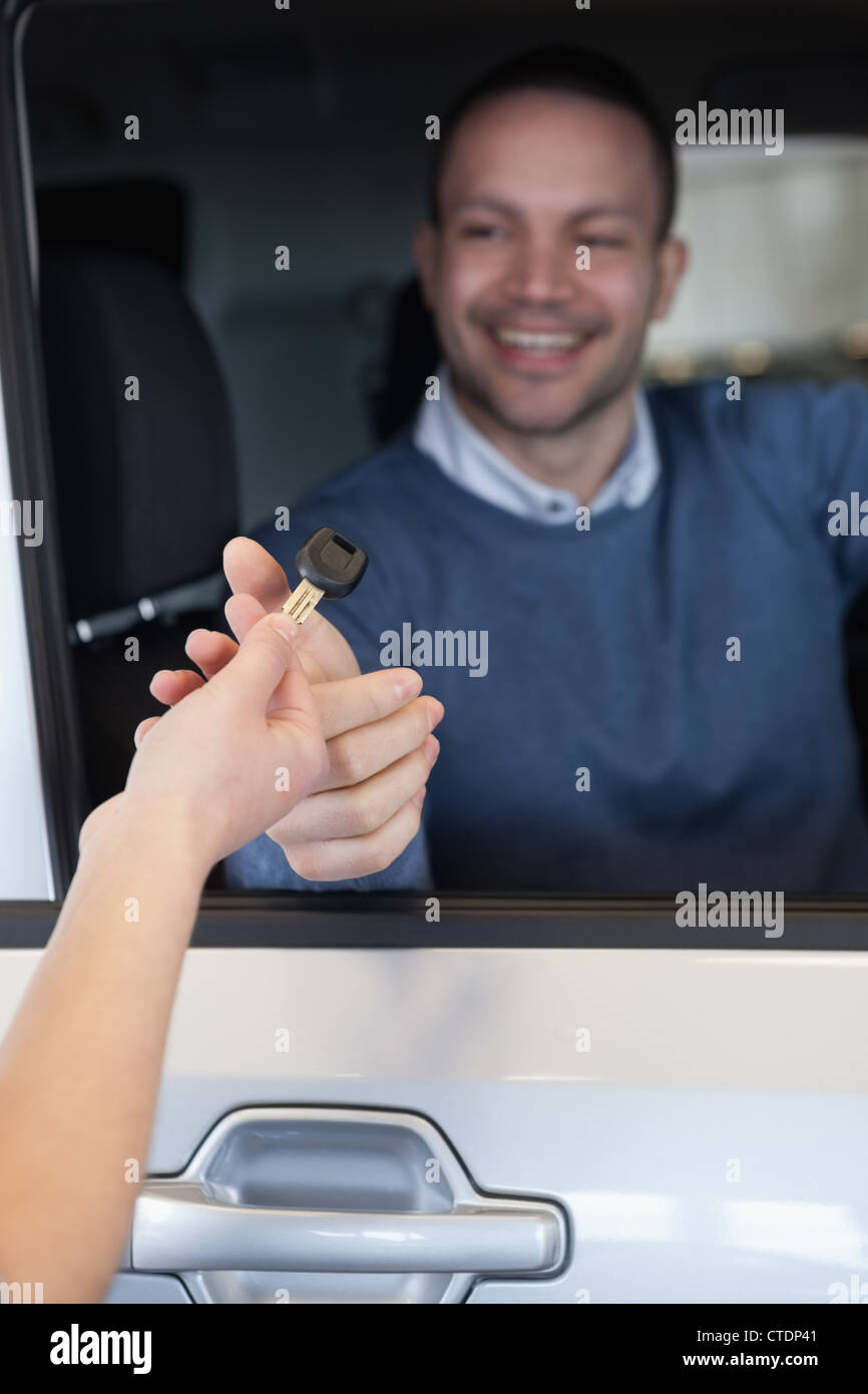 Man in a car receiving a key Stock Photo - Alamy