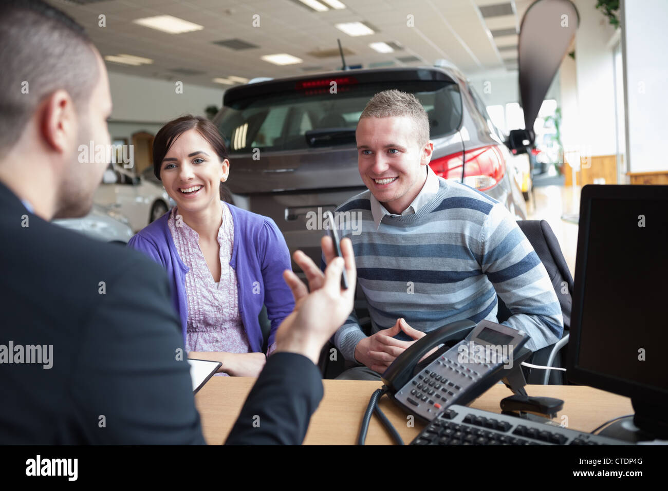 Couple smiling while talking with a salesman Stock Photo - Alamy