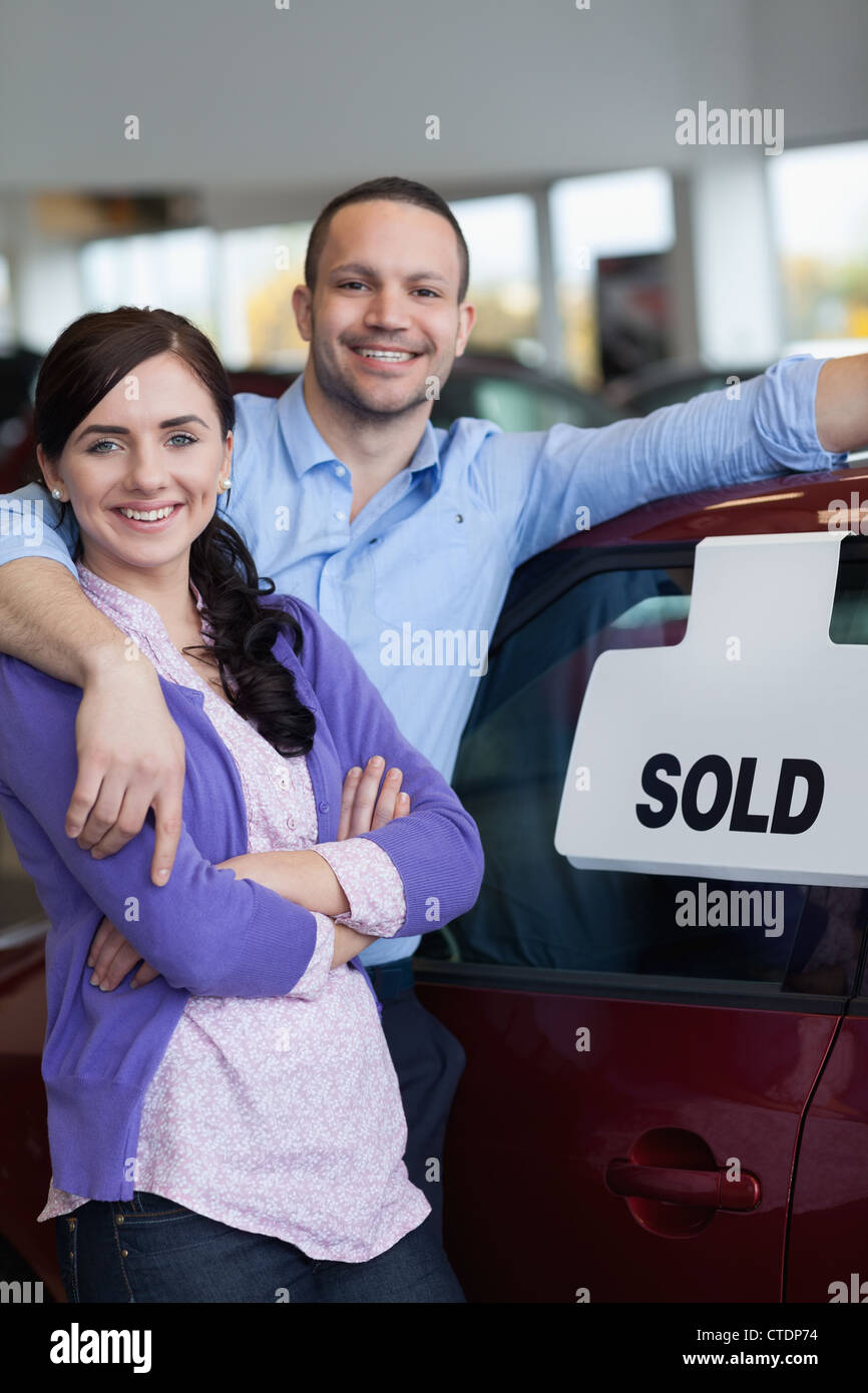Smiling couple hugging in front of a car Stock Photo - Alamy