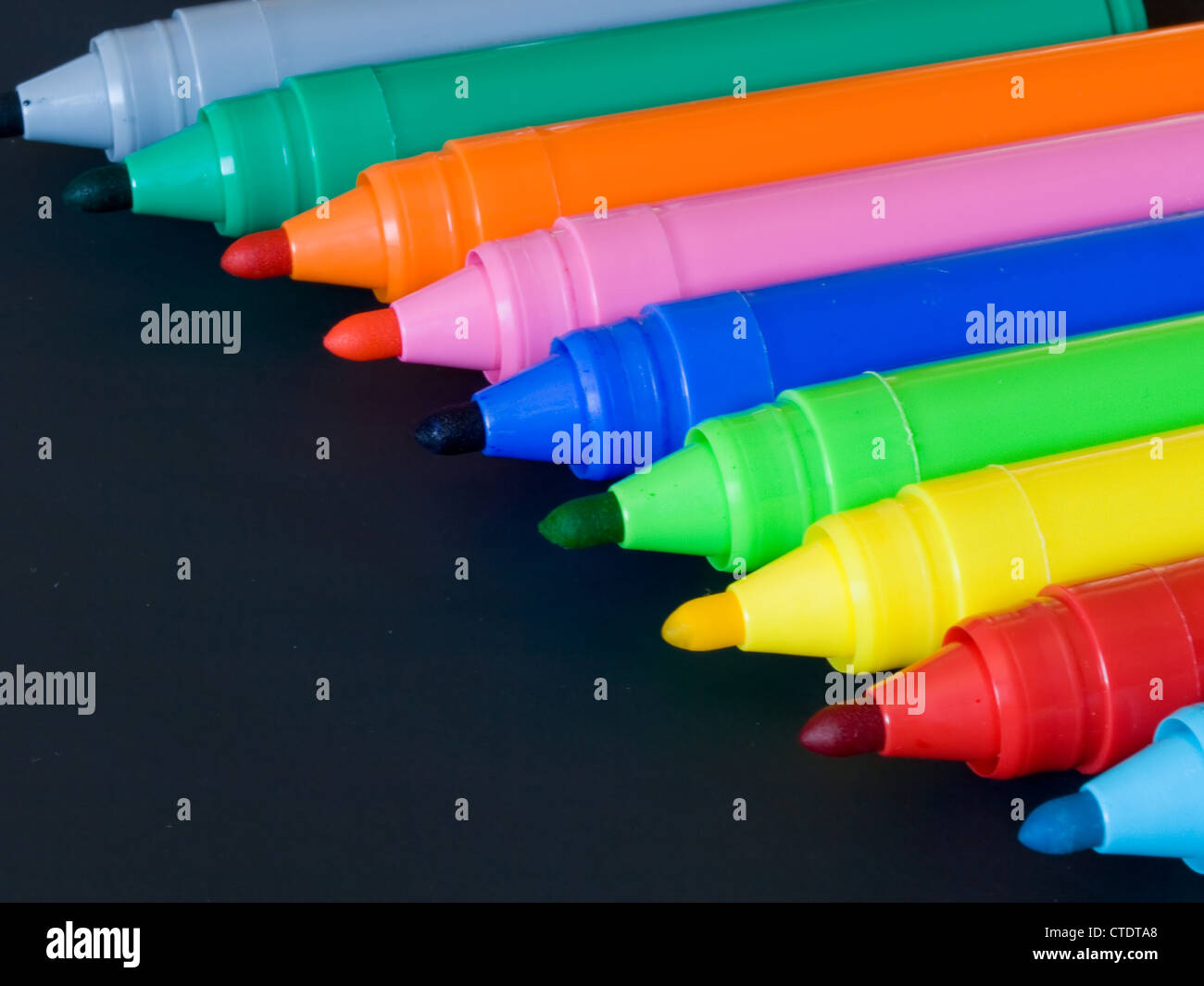 Several colored felt pens with caps off isolated on black background ...
