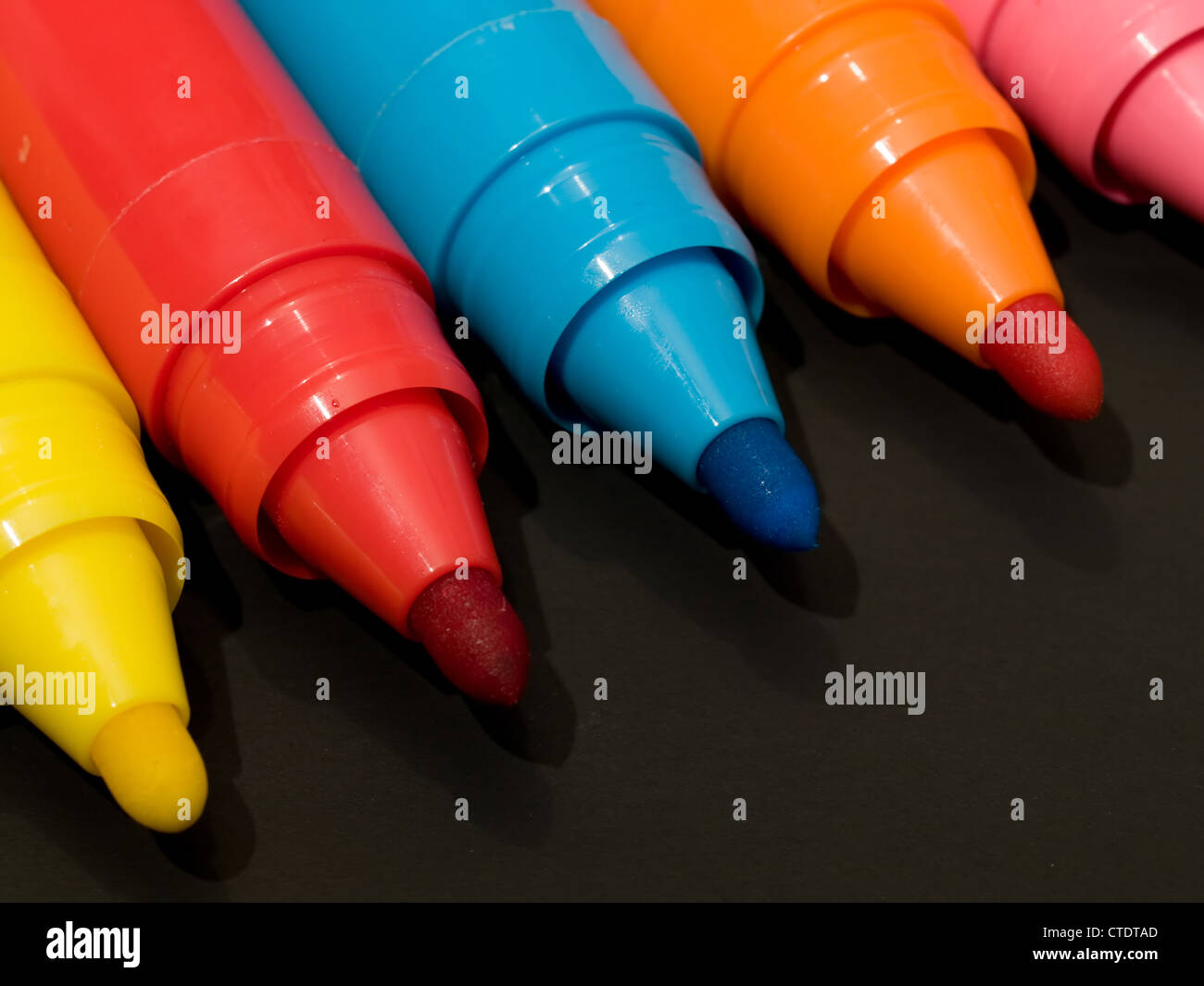 Several colored felt pens with caps off isolated on black background ...