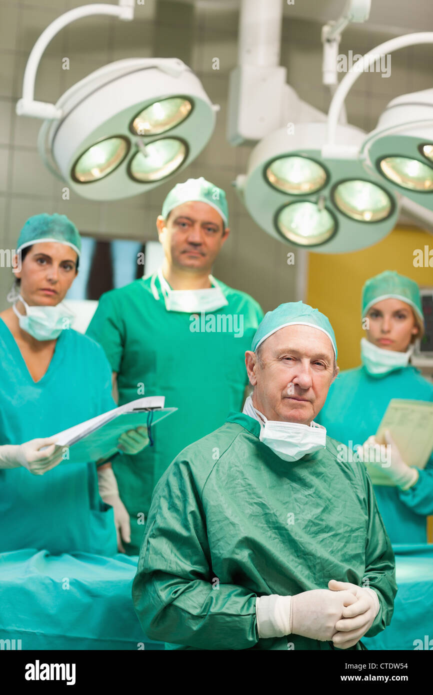 Surgeon sitting while crossing his hands with a team behind him Stock ...