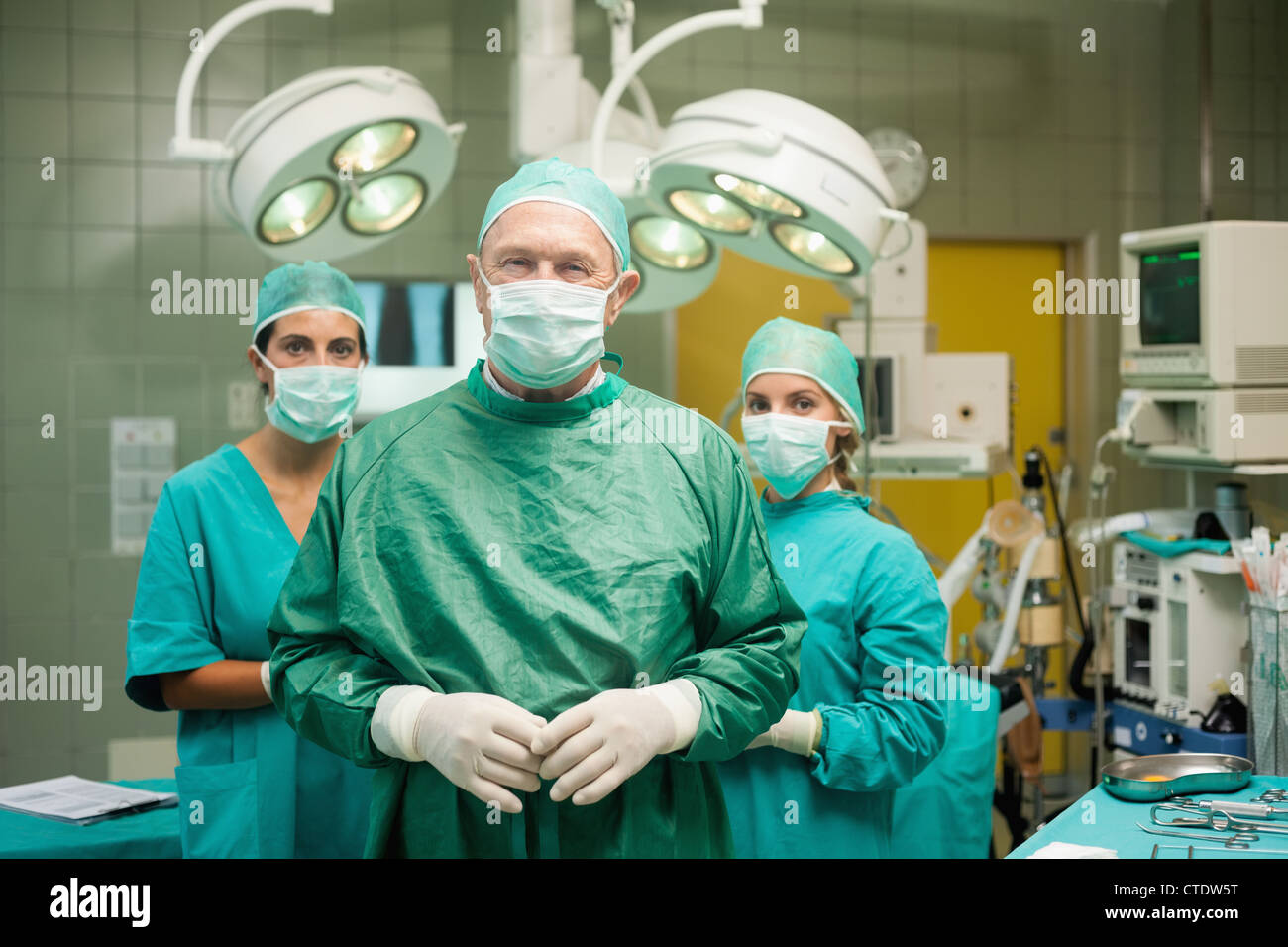 Surgeon joining his hand with two interns behind him Stock Photo - Alamy