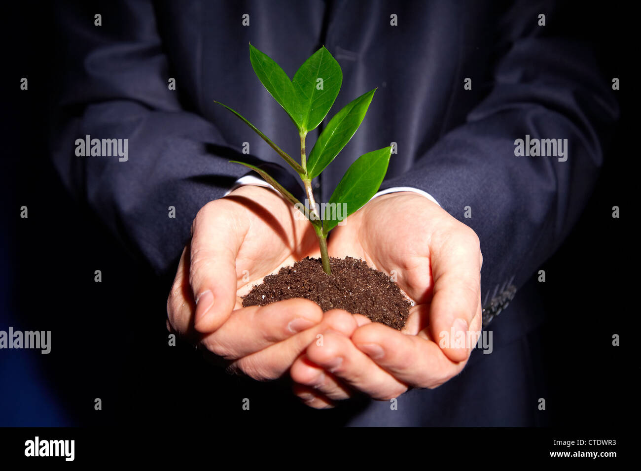 Unrecognizable person in formal suit holding a handful of soil with a ...