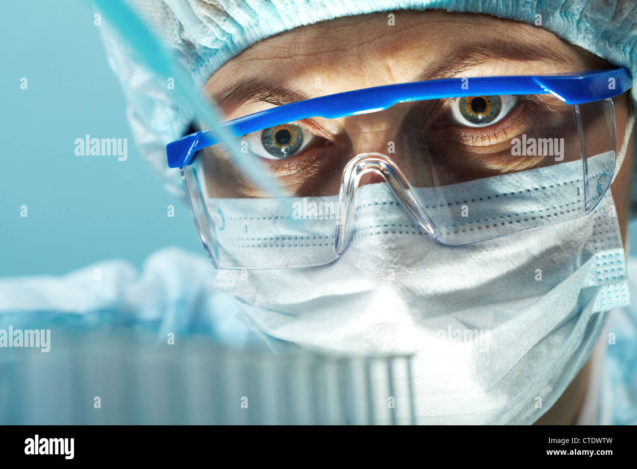Female lab worker staring at the pipette with a sample of substance ...