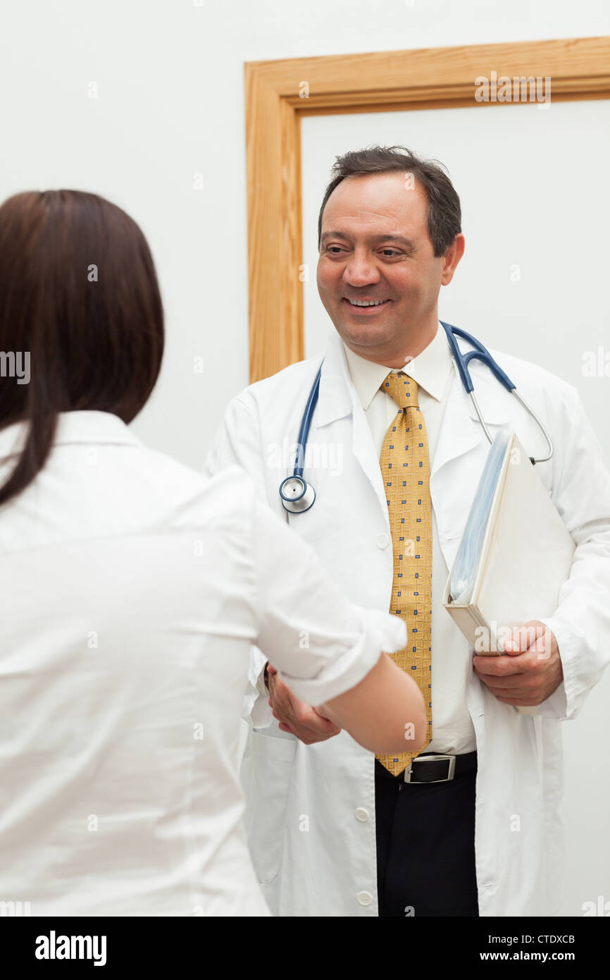 Doctor shaking the hand of a patient while holding a file Stock Photo ...