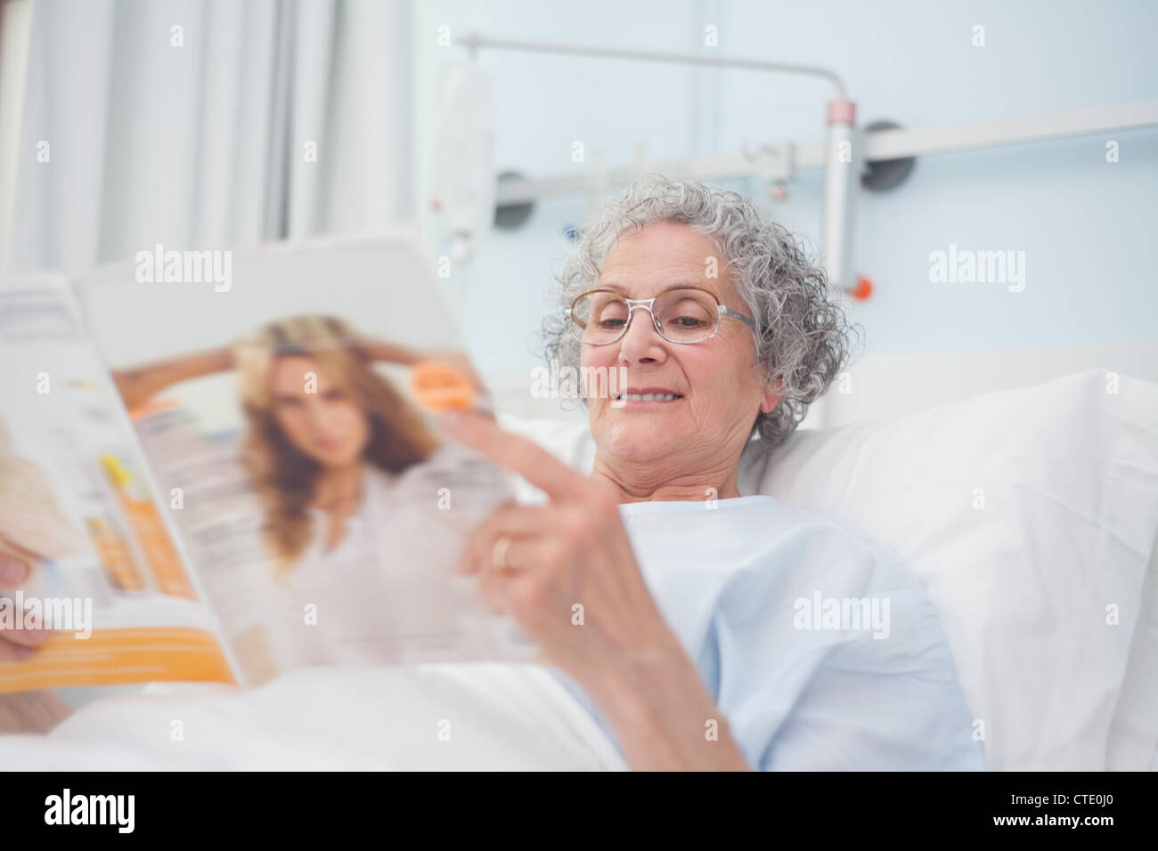 Elderly patient reading a magazine on her bed Stock Photo - Alamy