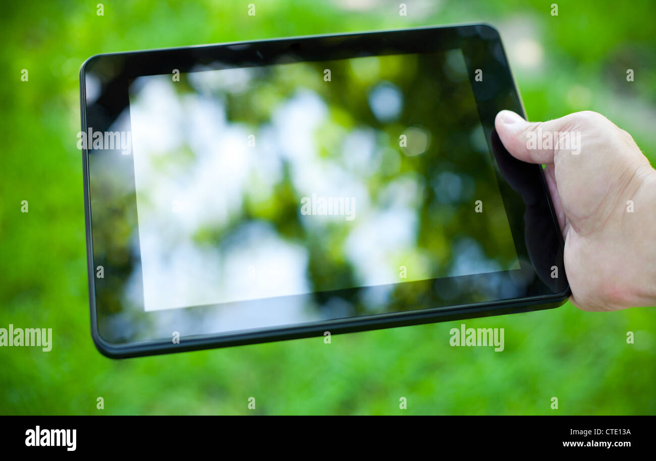 Man uses tablet computer outdoor, green graas on the background Stock ...