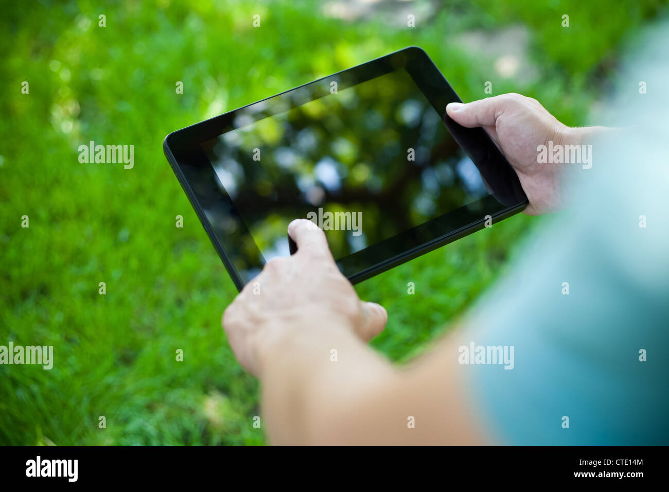 Man uses tablet computer outdoor, green graas on the background Stock ...