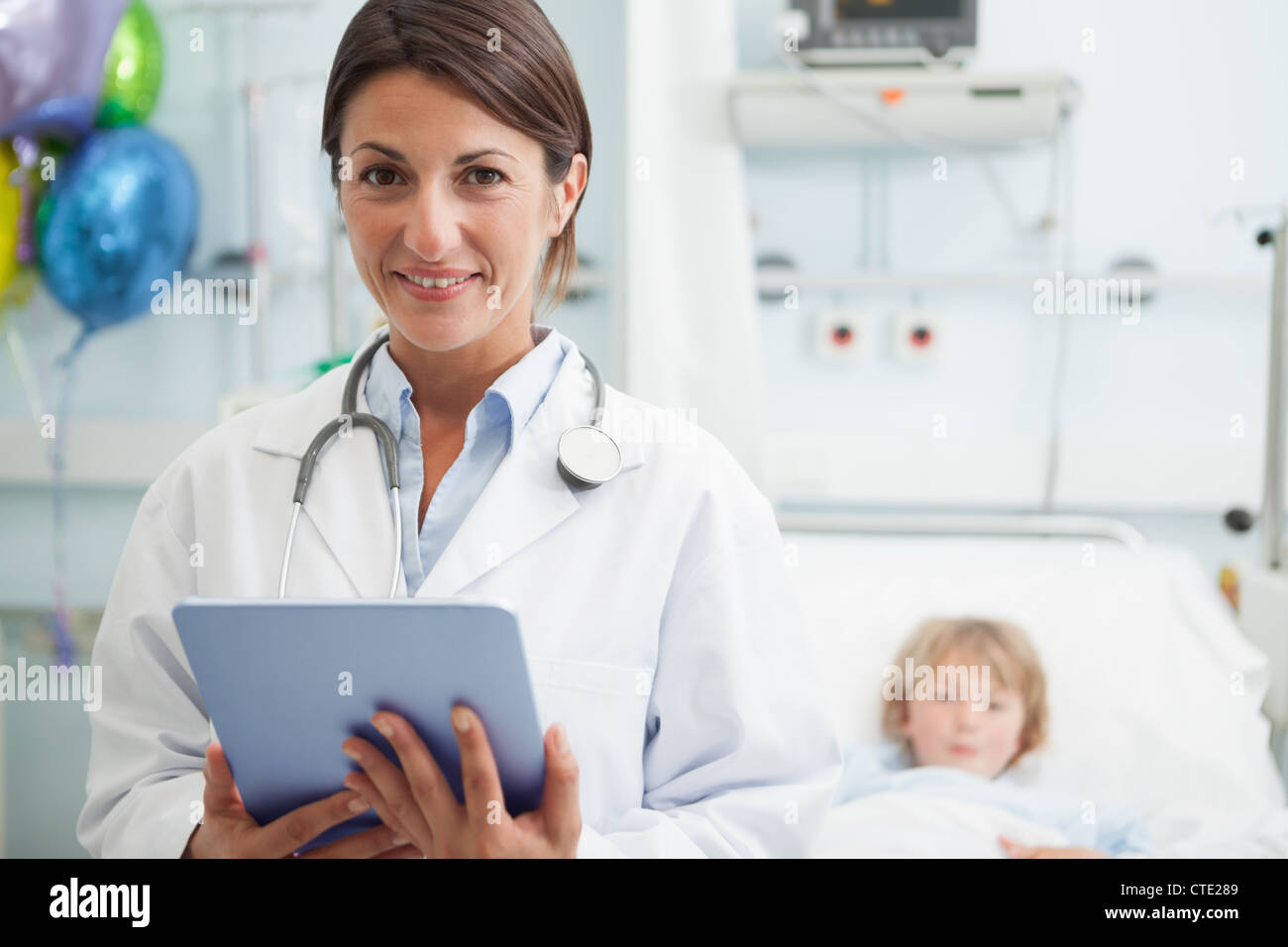 Doctor holding a tablet computer next to a child Stock Photo - Alamy