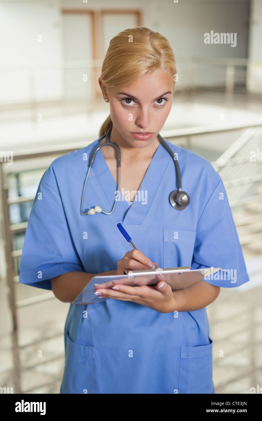 Serious nurse writing on a clipboard Stock Photo - Alamy
