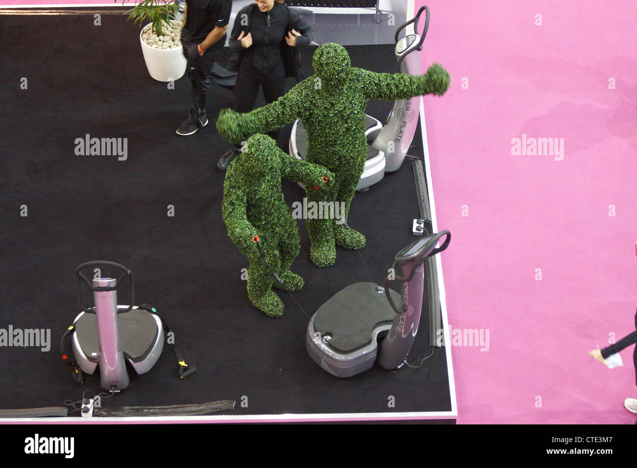 Two performers dressed as hedges try out exercise machines at the 2012 ...