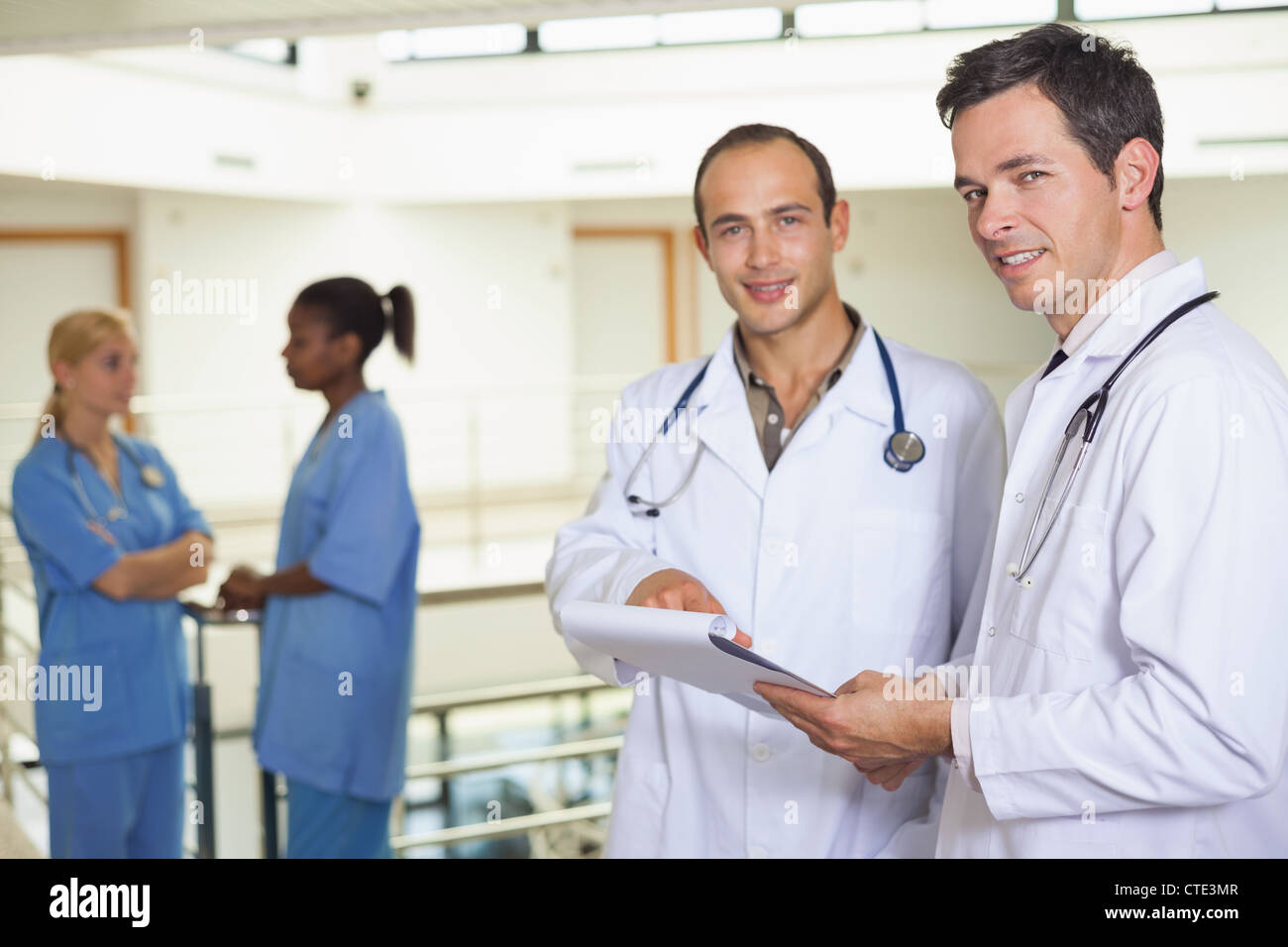 Doctors looking at camera next to nurses Stock Photo - Alamy