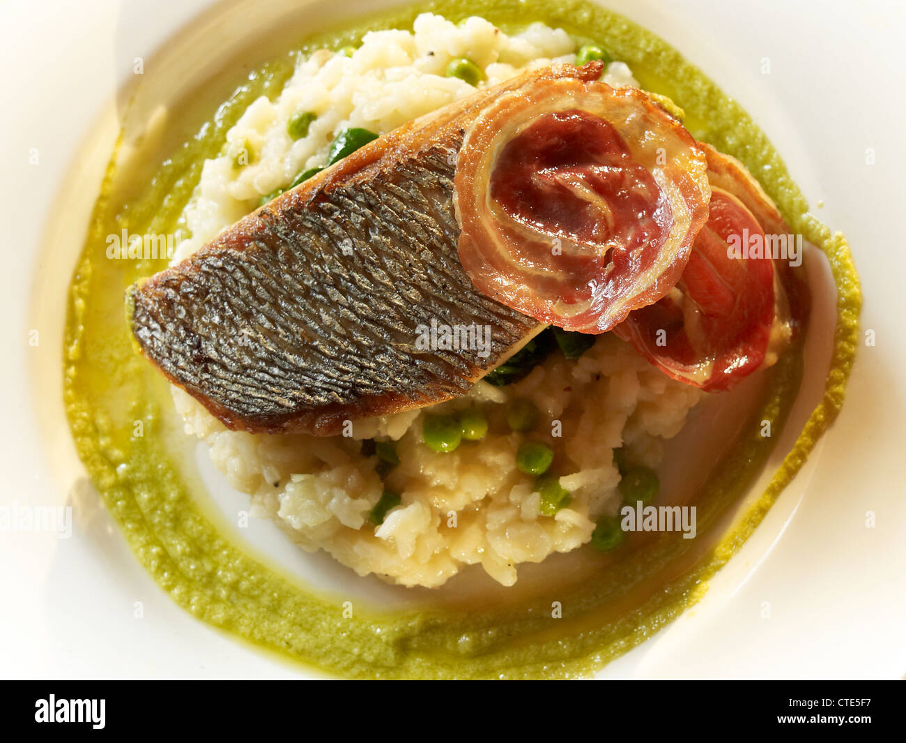 photograph of pan fried fish / cod on a bed of mash and peas with bacon ...