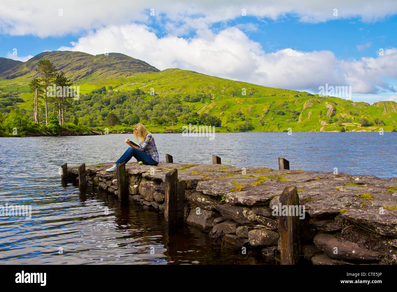 A woman reading a book by the lake Stock Photo - Alamy