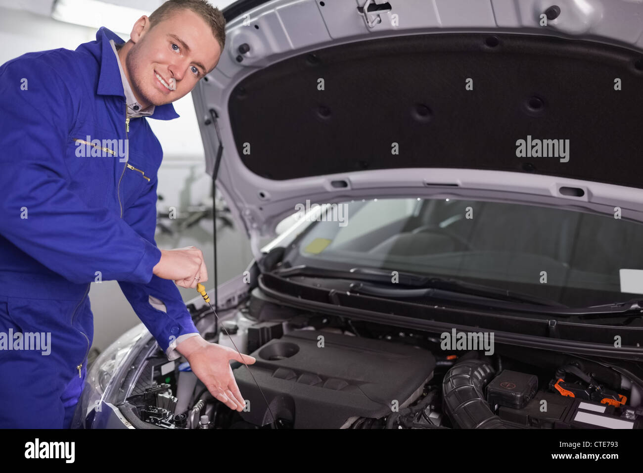 Mechanic showing an engine with his hand Stock Photo - Alamy