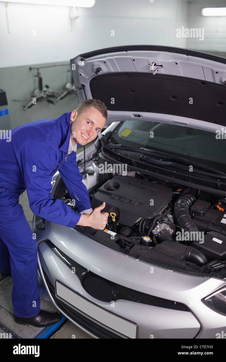 Mechanic leaning on a car while looking at camera Stock Photo - Alamy