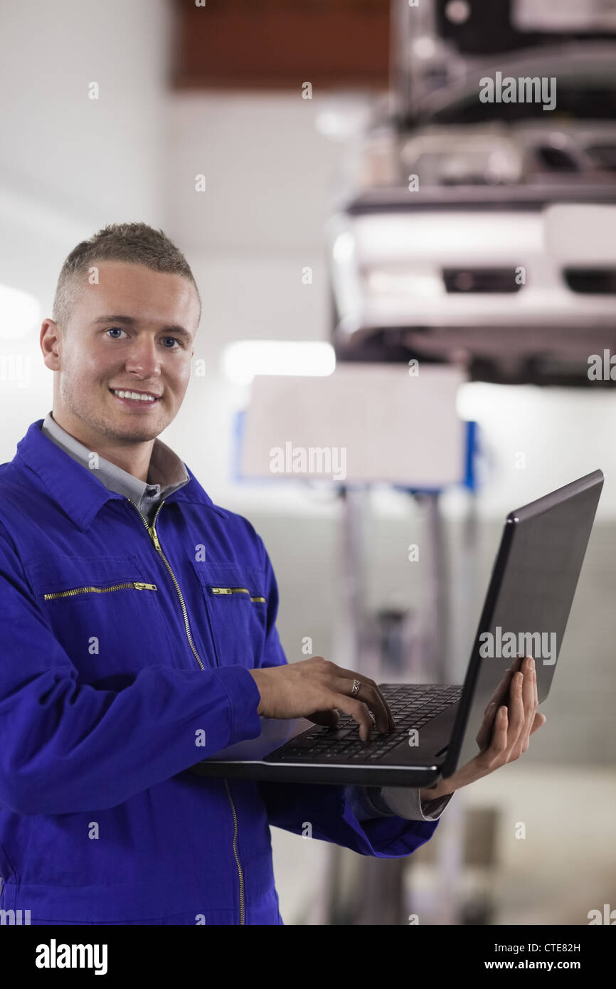 Smiling mechanic typing on a laptop Stock Photo - Alamy
