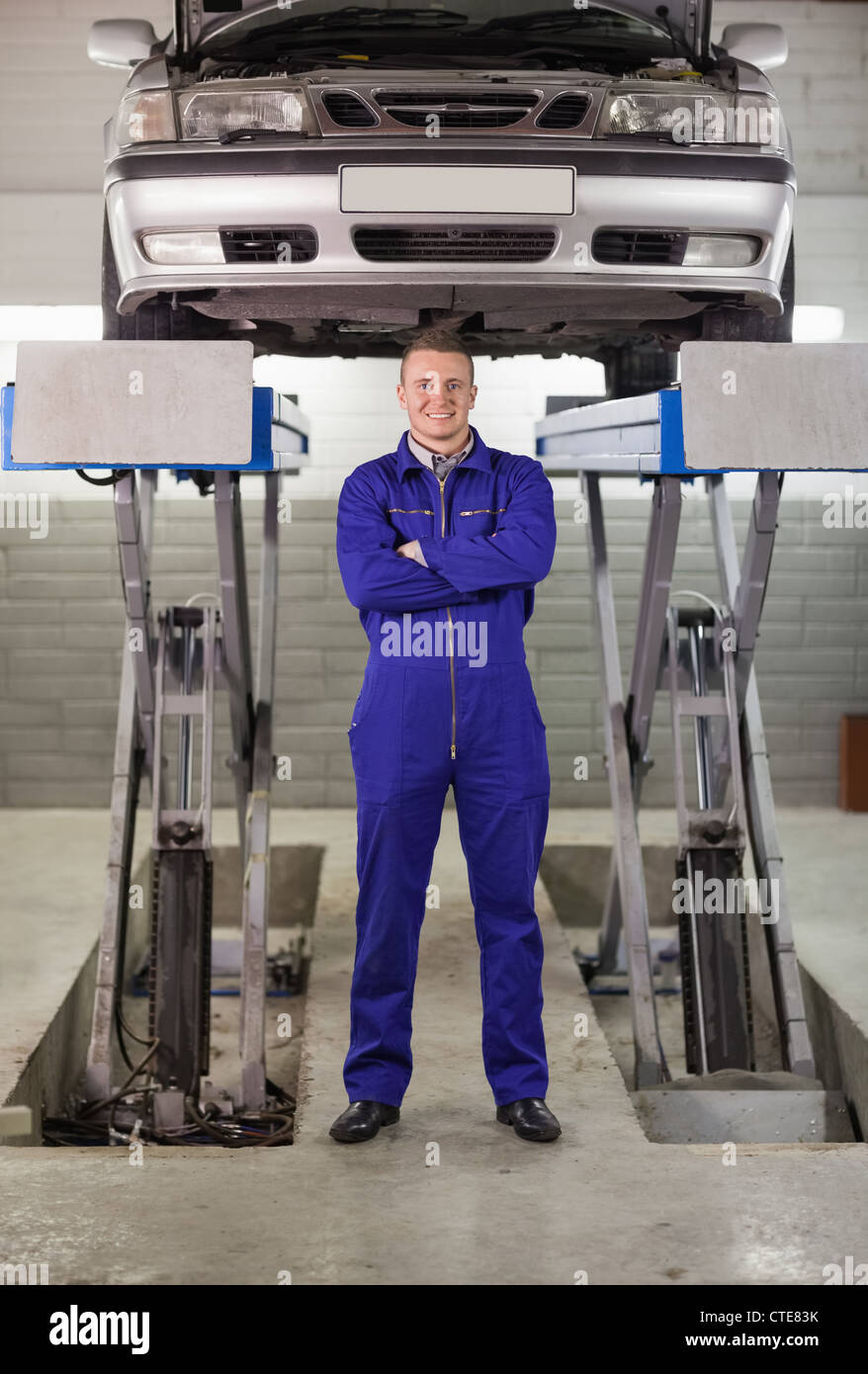 Mechanic standing with arms crossed below a car Stock Photo - Alamy