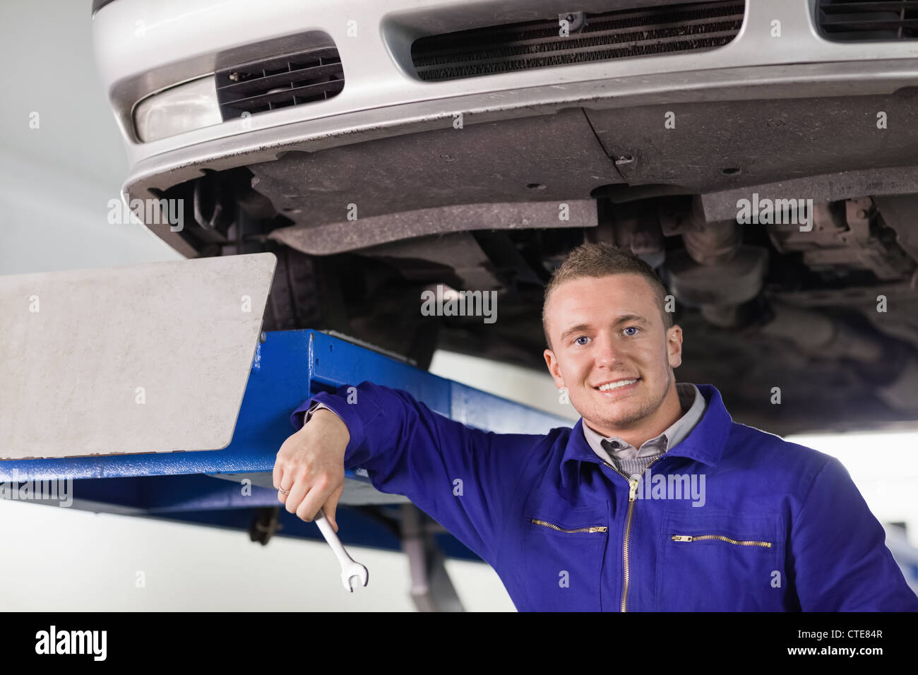 Mechanic holding a spanner below a car Stock Photo - Alamy