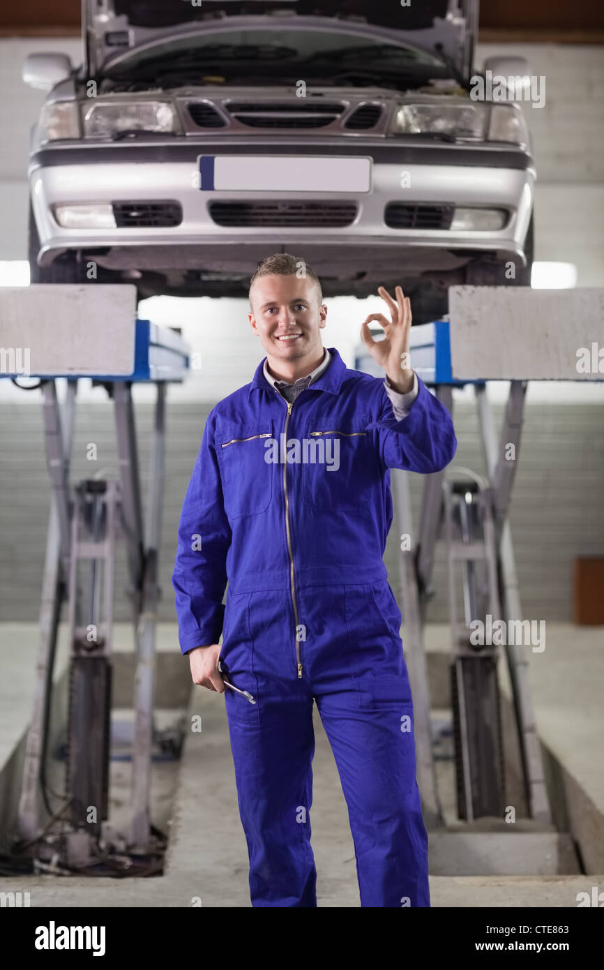 Mechanic standing doing a gesture with his fingers Stock Photo - Alamy