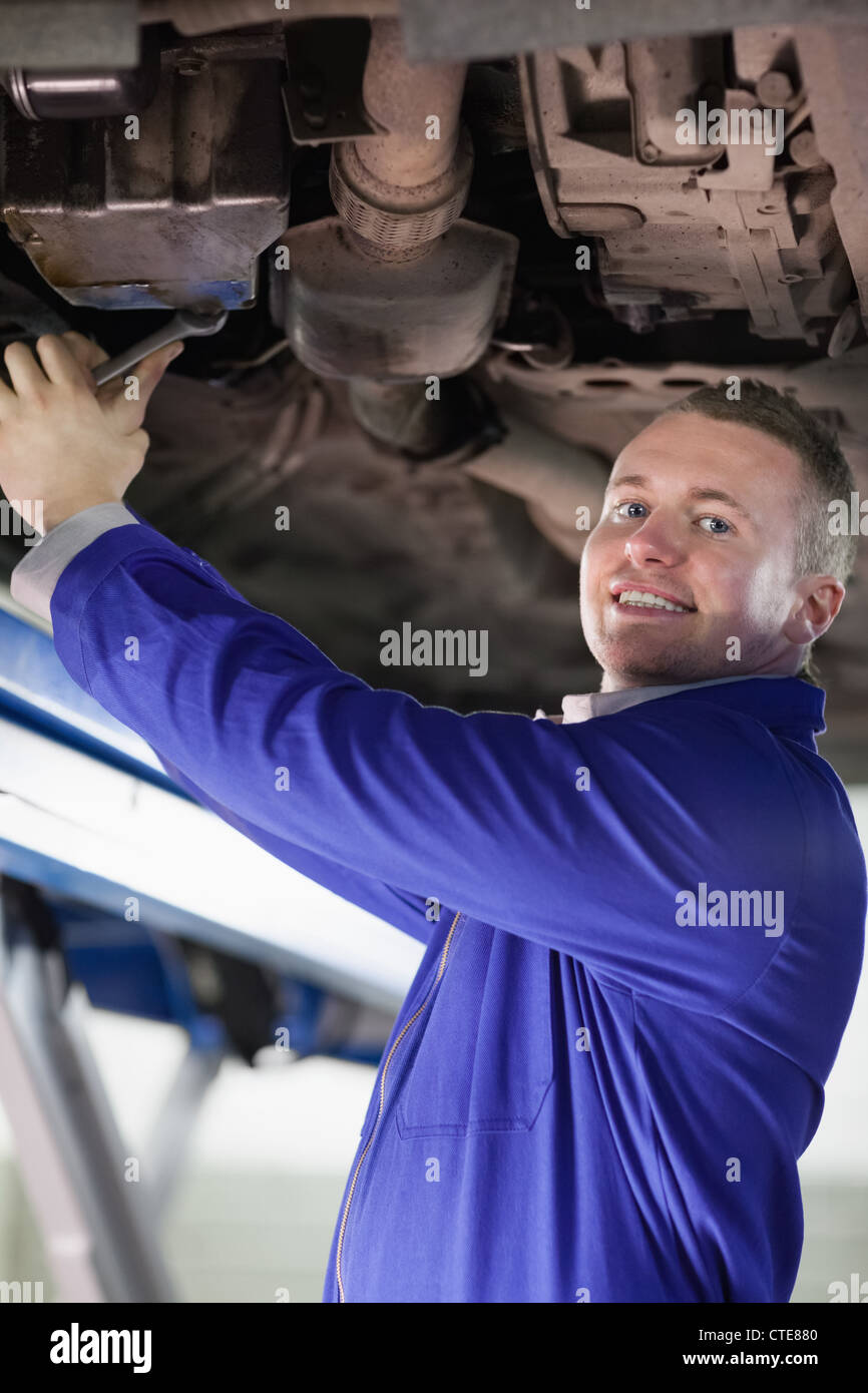 Smiling mechanic repairing a car Stock Photo - Alamy