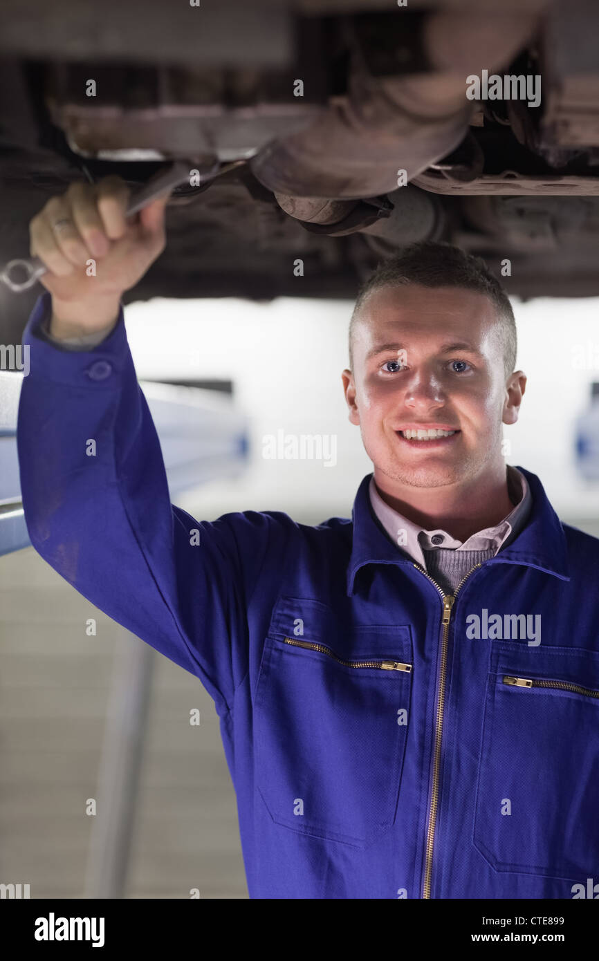 Smiling mechanic repairing the below of a car with a spanner Stock ...
