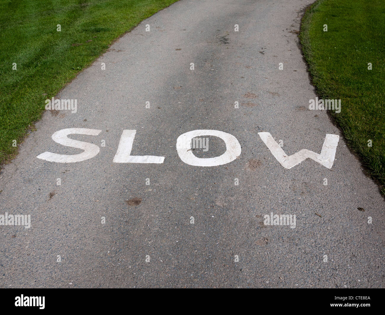 Slow sign painted on tarmac road Stock Photo - Alamy