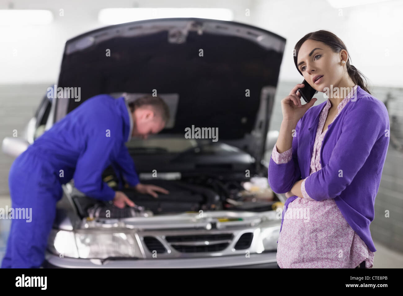 Woman calling next to a mechanic Stock Photo - Alamy