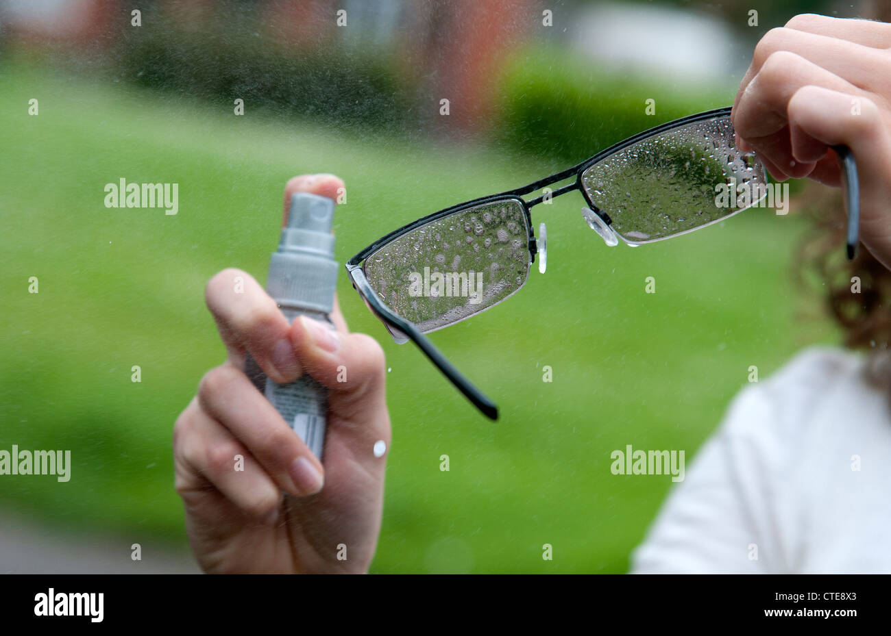 Cleaning spectacles with a spray on cleaner Stock Photo - Alamy