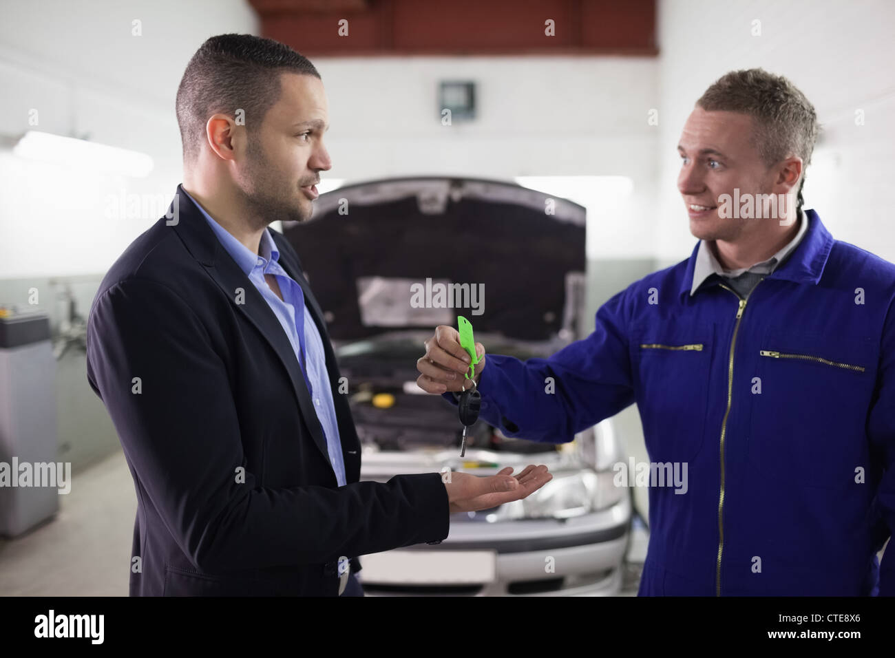 Mechanic giving car key to a man Stock Photo - Alamy